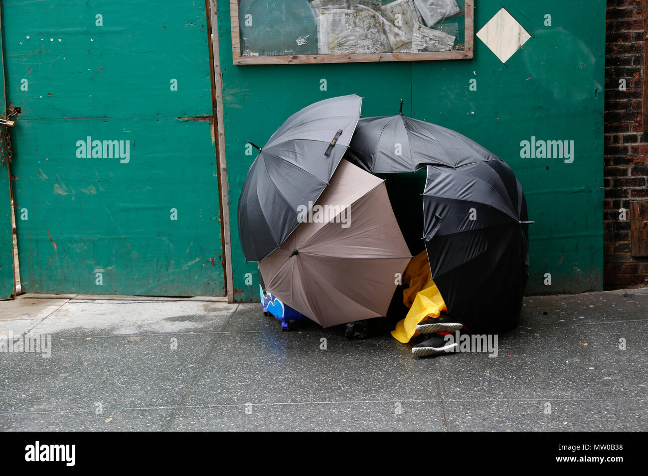 Creative homeless person builds a tent on the sidewalk with umbrellas ...