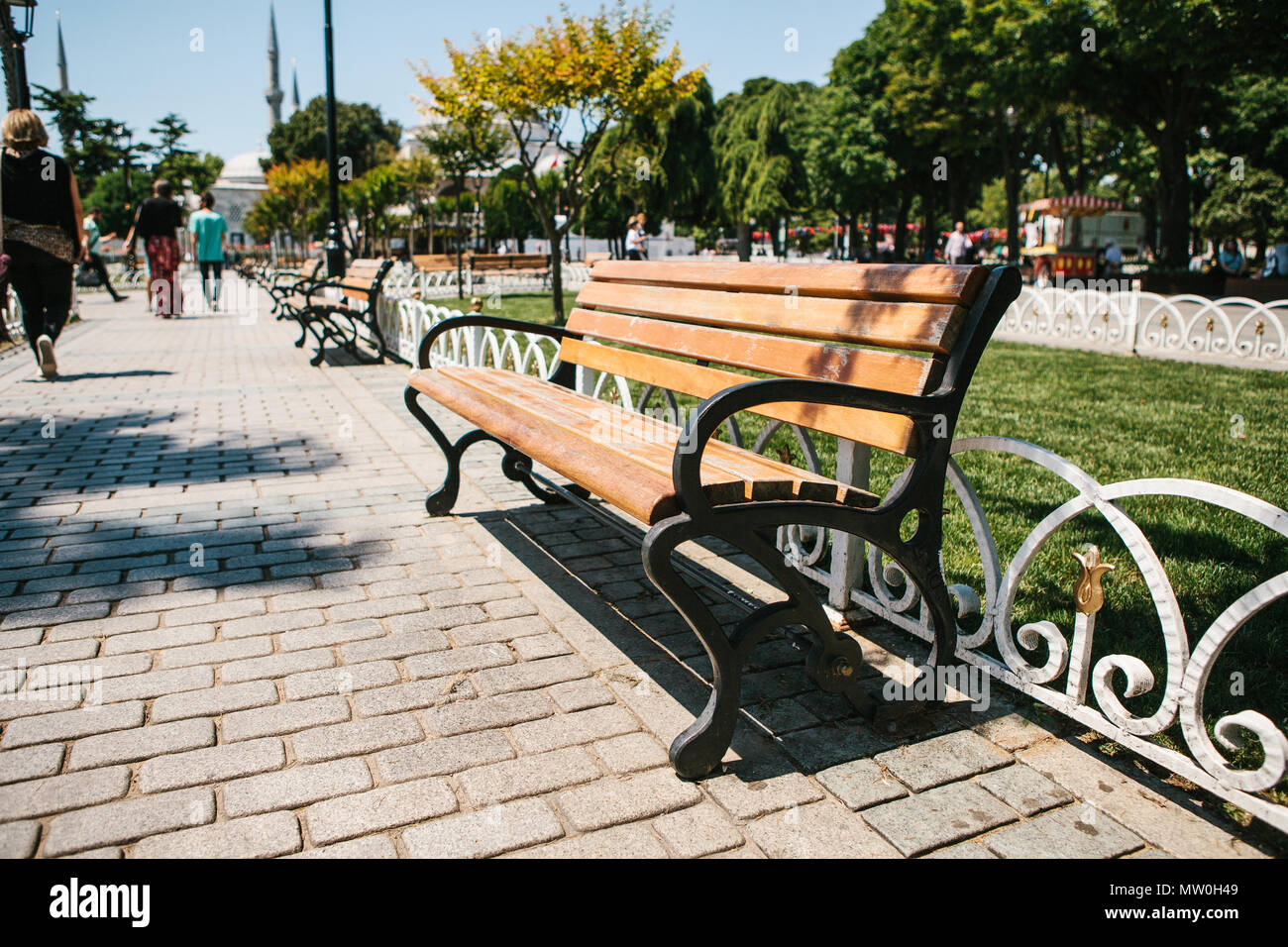 Public space. Benches in sunny park with alleys against the background ...