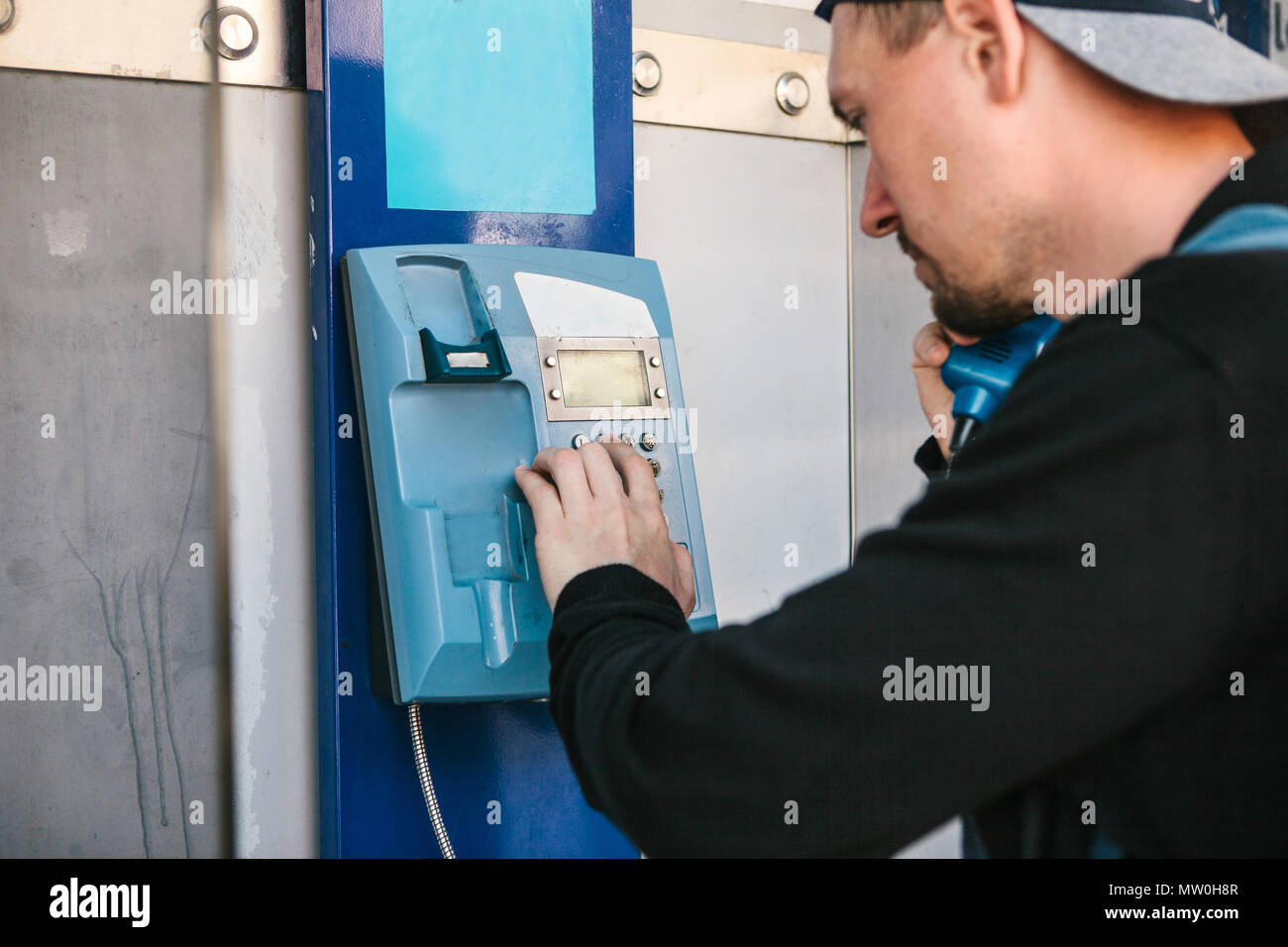 Young attractive modern man talking on the payphone, communication ...
