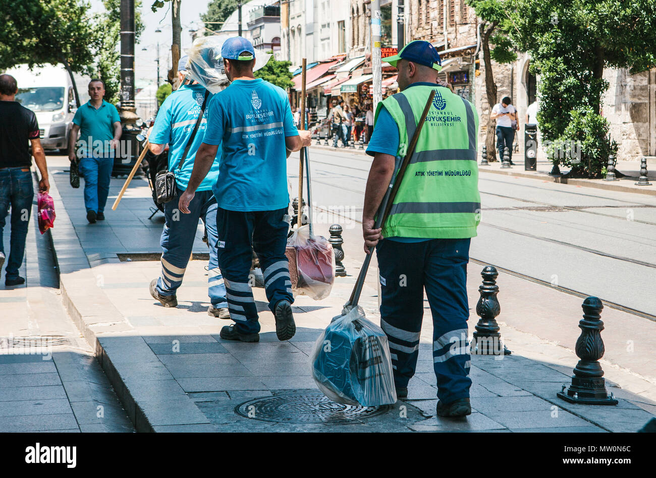 Editorial image of three street janitors in uniforms are walking down ...