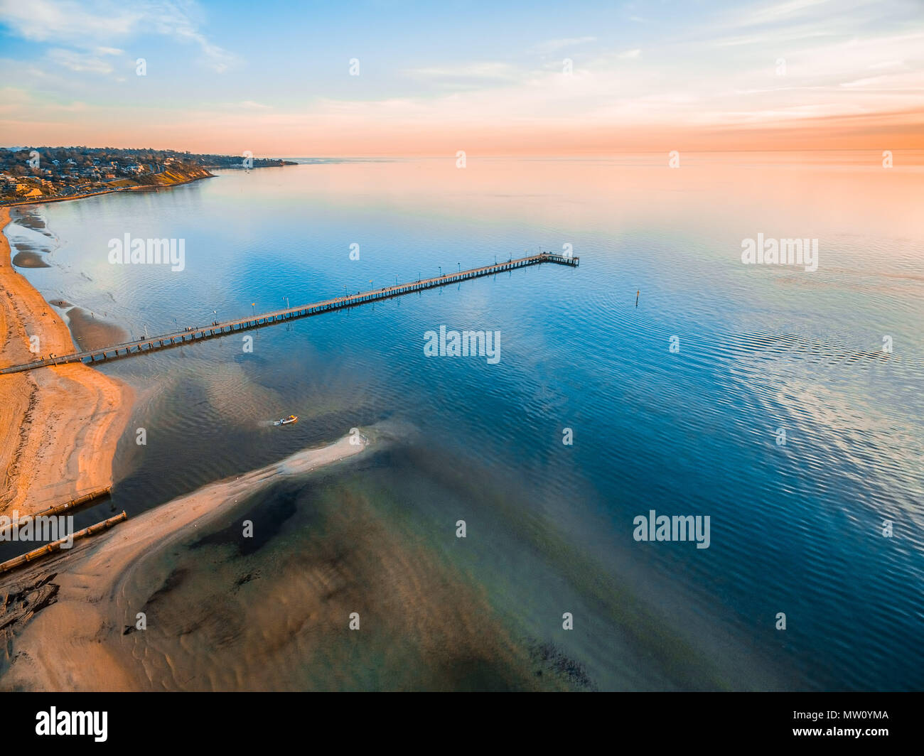 Pier extending into calm bay water at sunset - aerial view Stock Photo ...