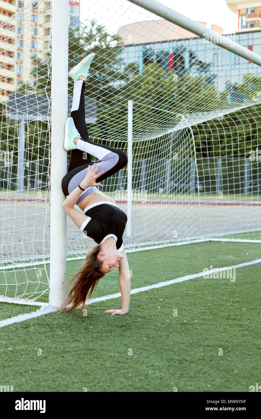 Young woman stands on one hand at the football goal Stock Photo - Alamy