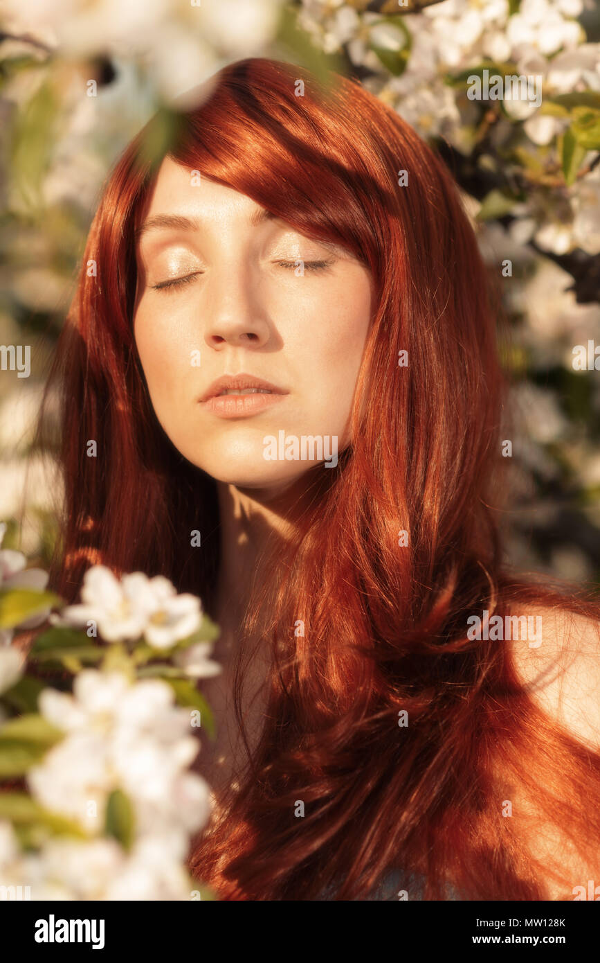 Woman with long red hair in Spring blossom Stock Photo - Alamy