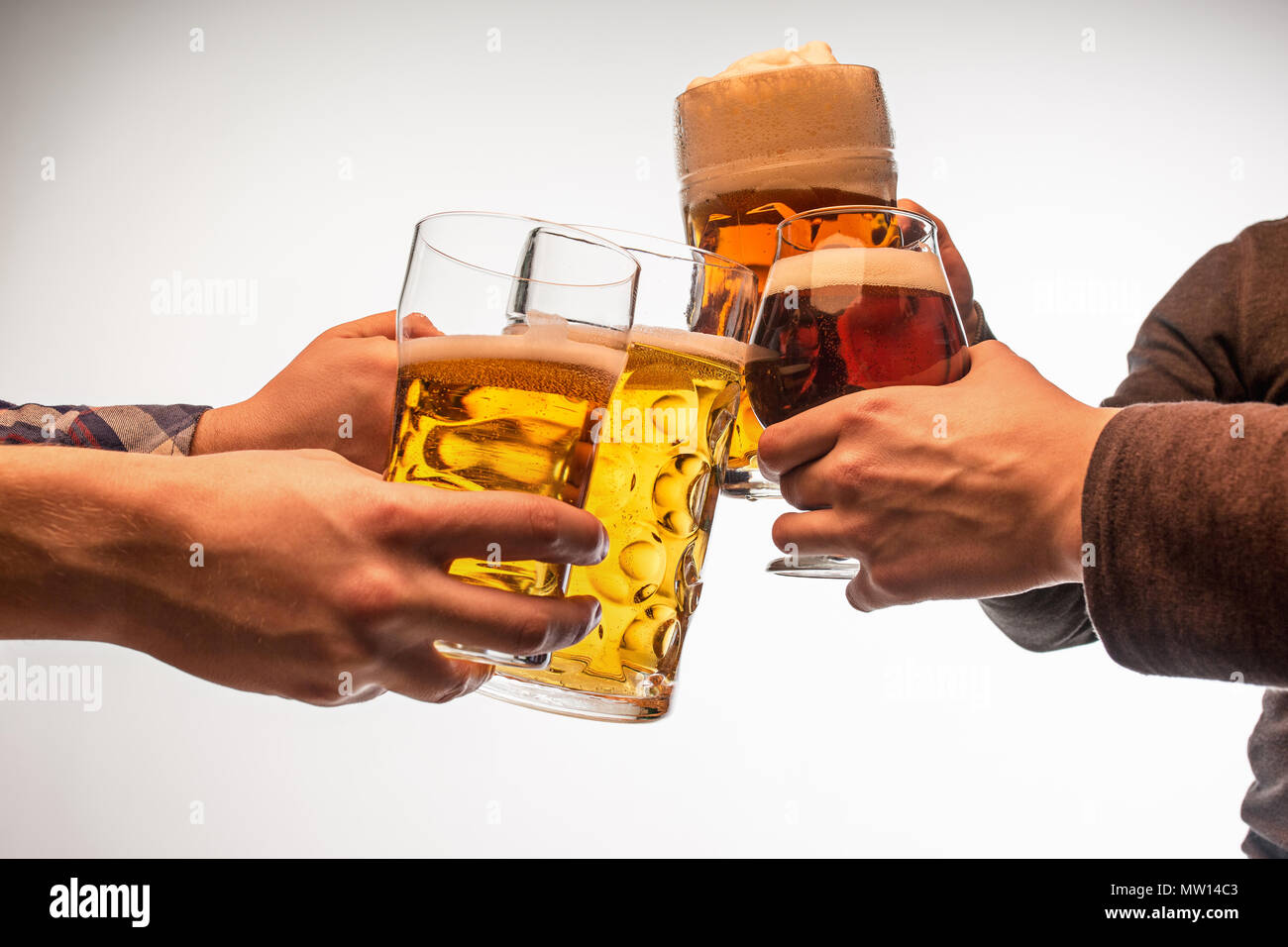 hands with mugs of beer toasting creating splash isolated on white ...