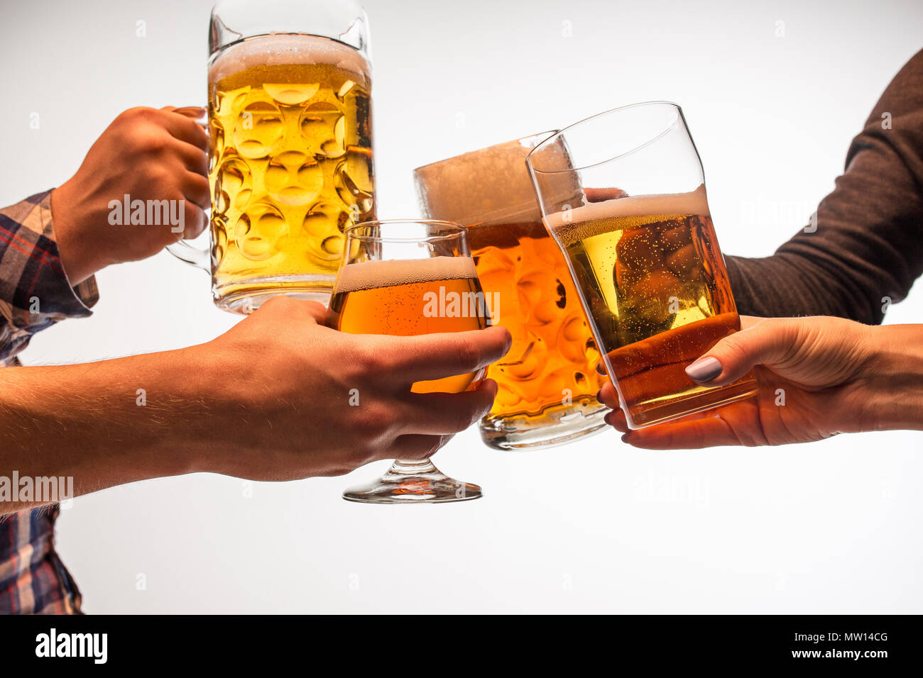 hands with mugs of beer toasting creating splash isolated on white ...