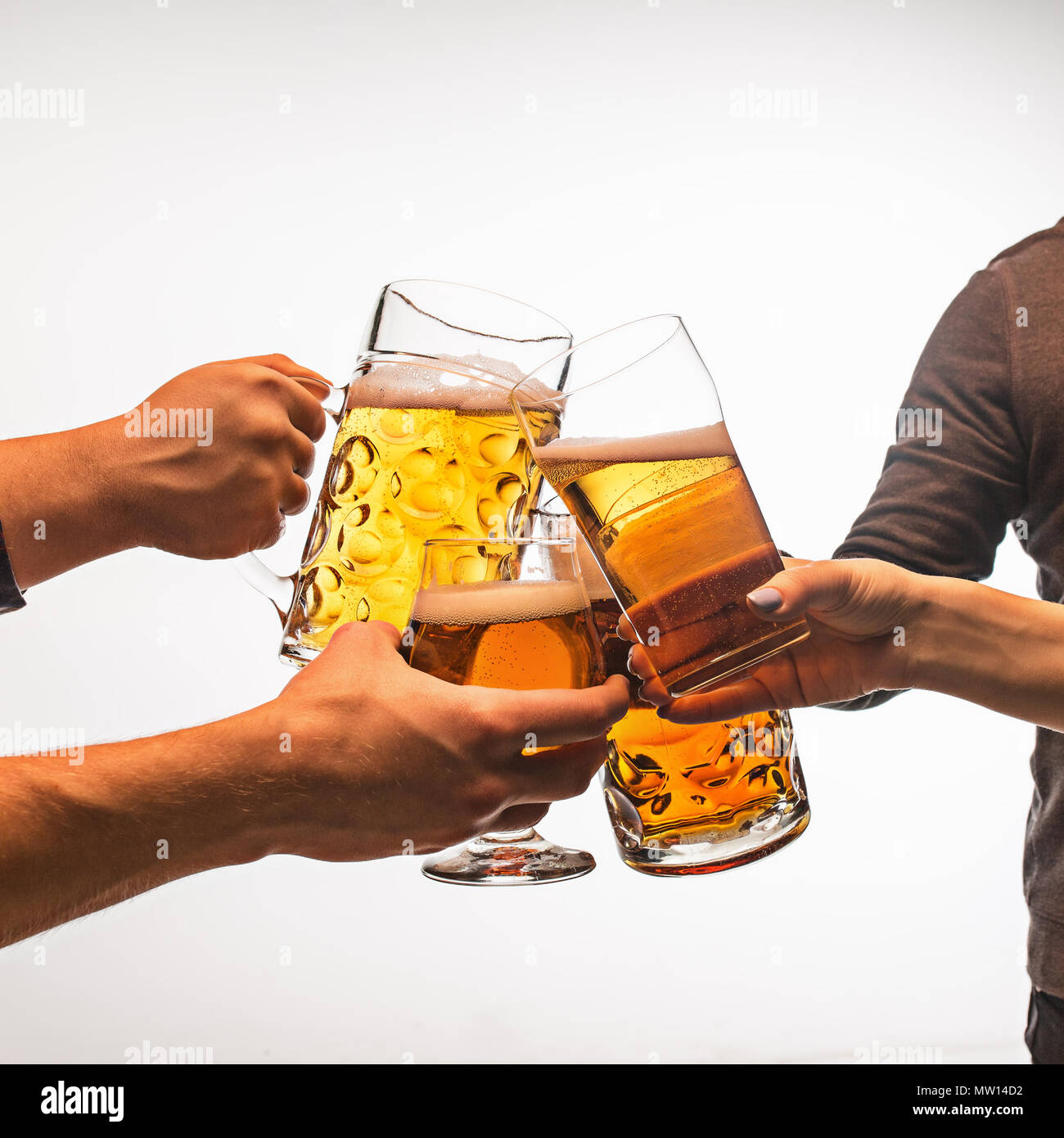 hands with mugs of beer toasting creating splash isolated on white ...