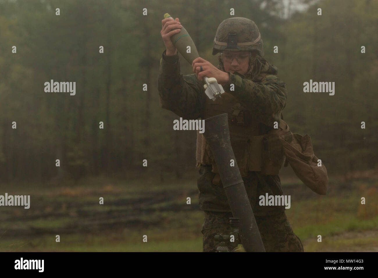 A Marine prepares to drop an 81mm mortar round into an M252 medium ...