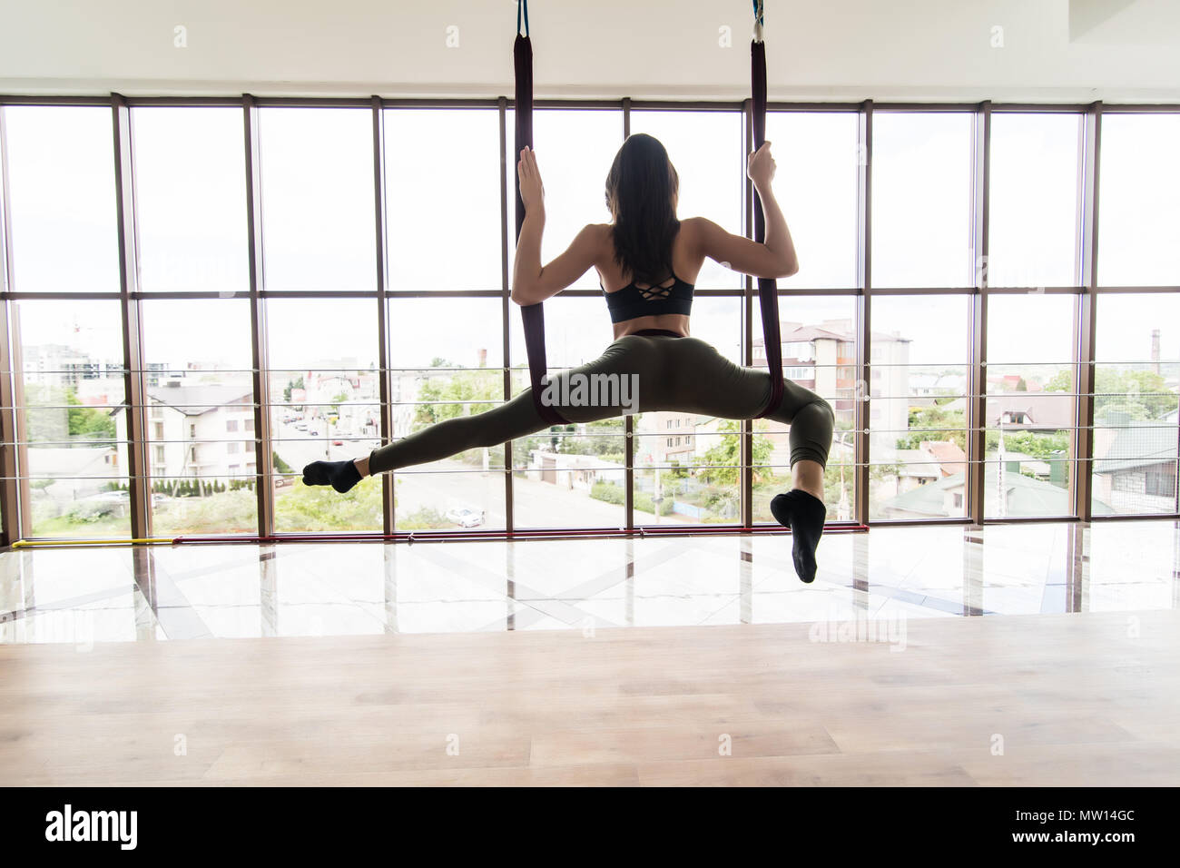 Fit young woman doing gravity fly yoga asana stretching exercises in ...