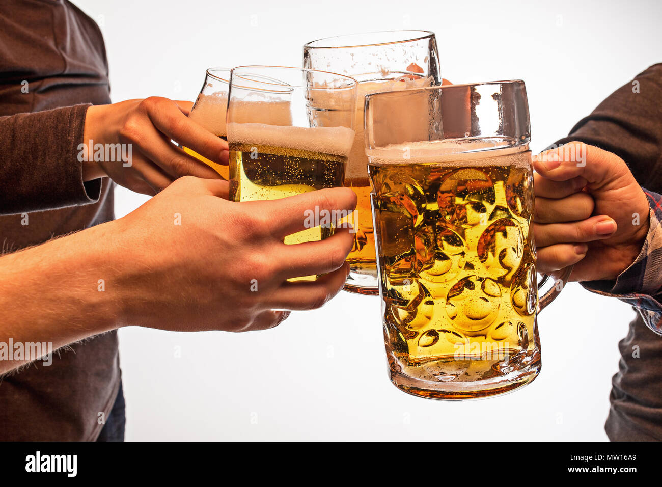 hands with mugs of beer toasting creating splash isolated on white ...