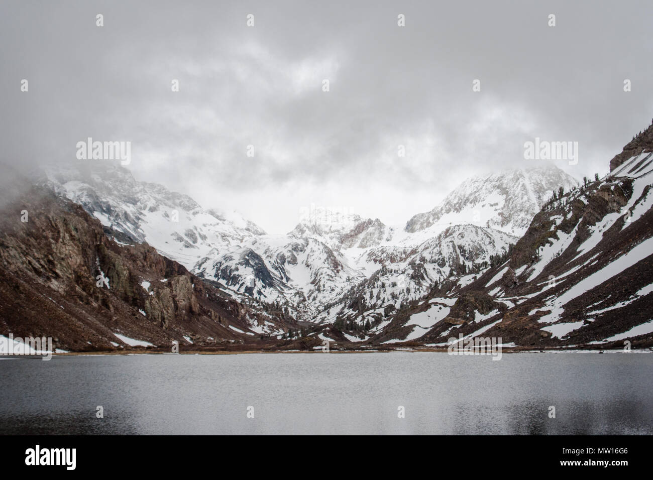 A lake in the Sierra Nevada Mountains in front of snow covered mountain ...