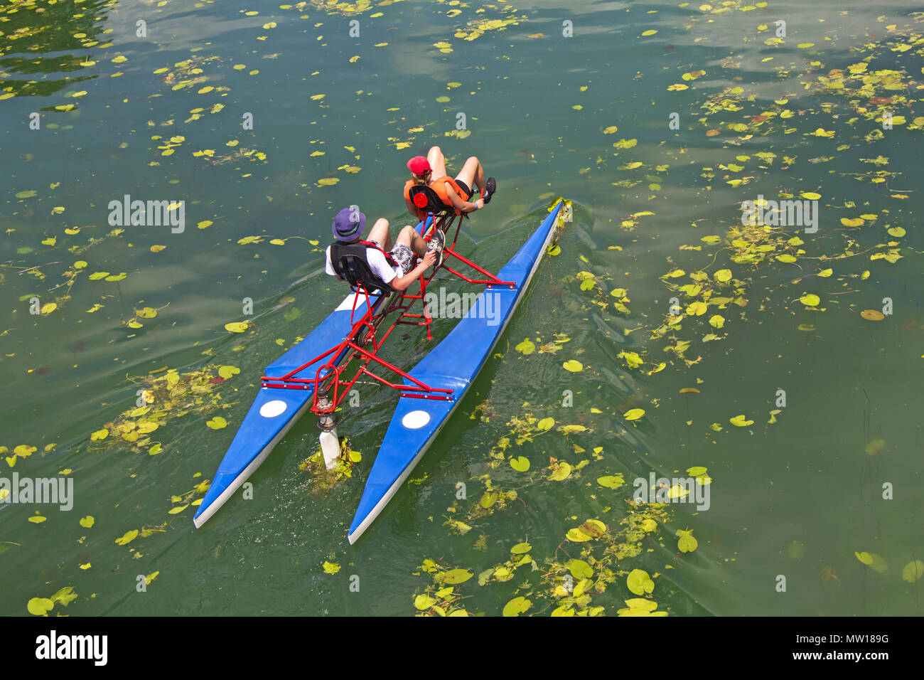 Man and woman ride with floating pedal bicycle boats across the lake ...