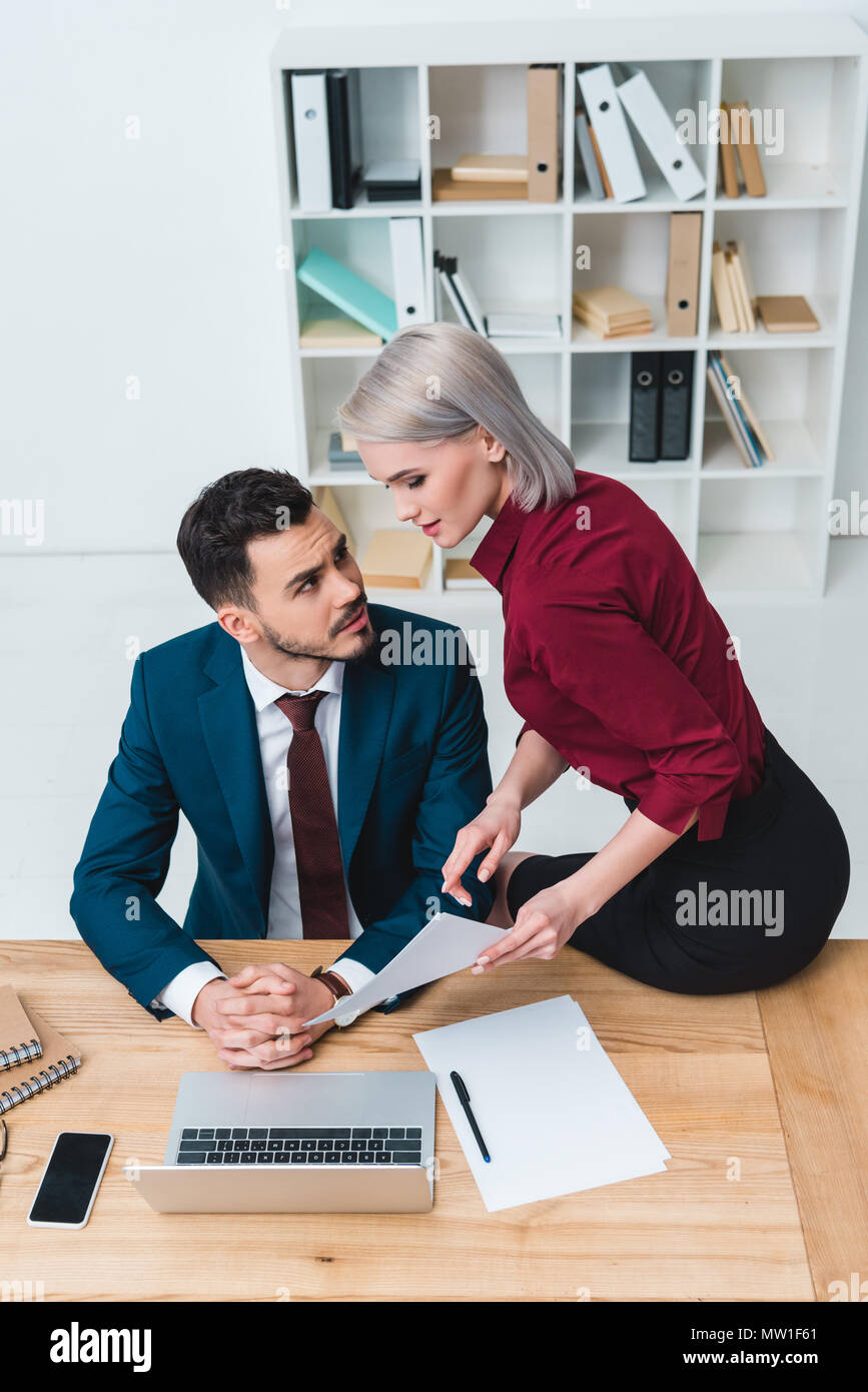 high angle view of young business colleagues flirting while working ...