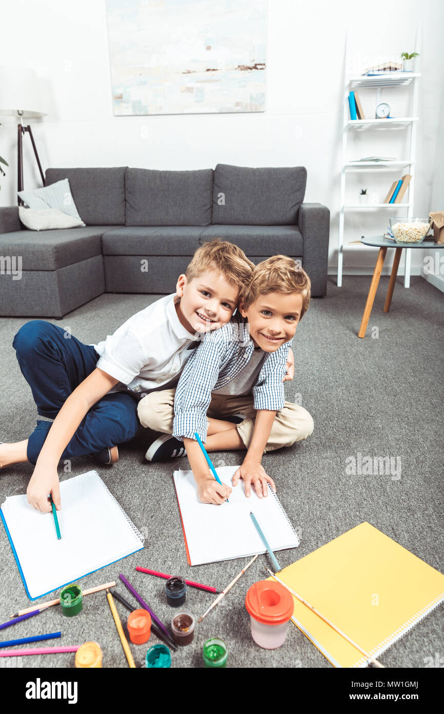 cute little boys drawing together and smiling at camera at home Stock ...