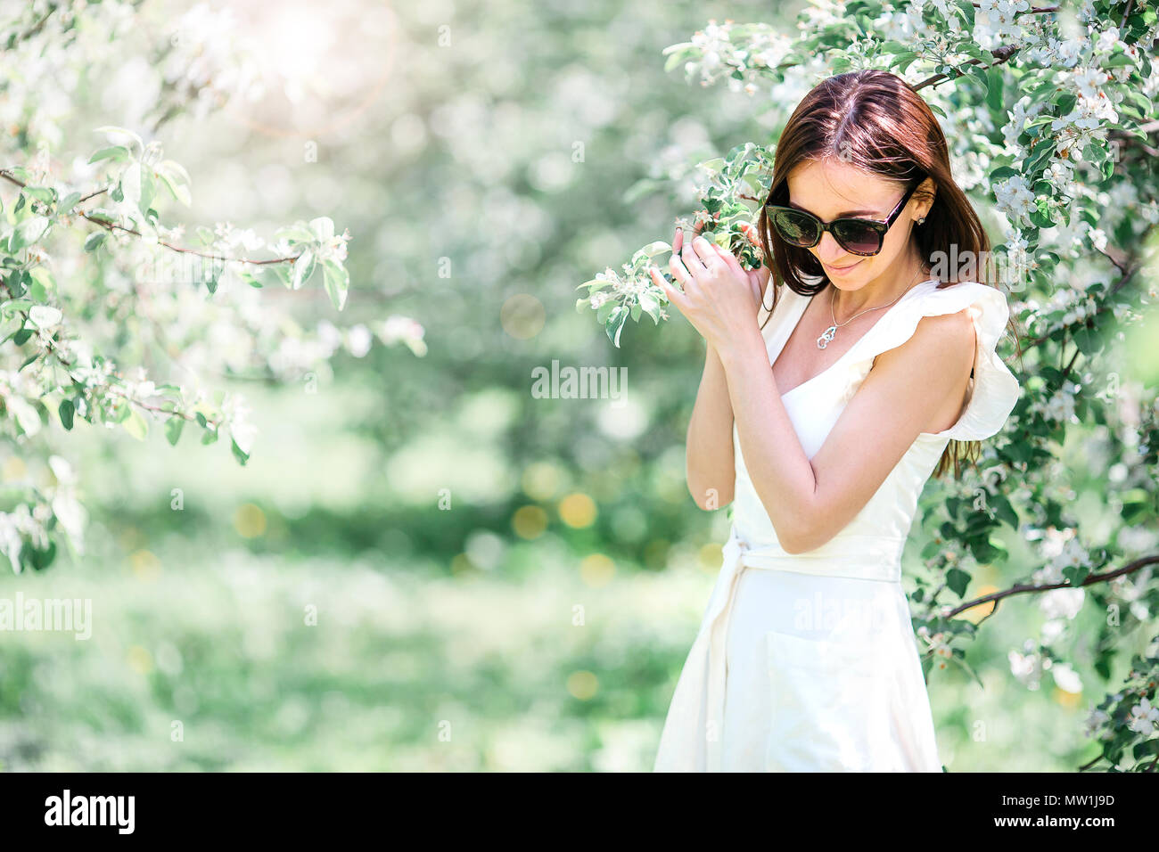 Beautiful woman enjoying smell in spring cherry garden Stock Photo - Alamy