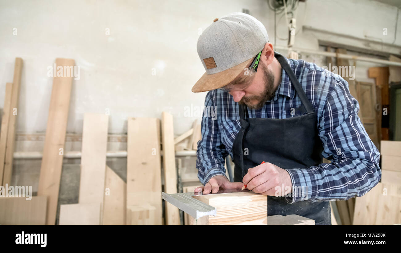 Close-up of craftsman hands in gloves measuring wooden plank with ruler ...