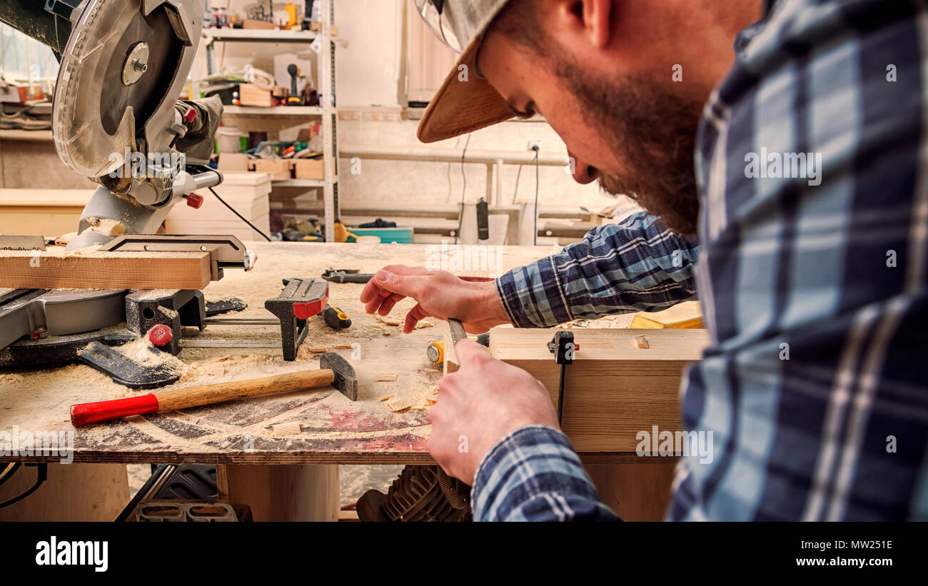 Close-up of craftsman hands in gloves measuring wooden plank with ruler ...