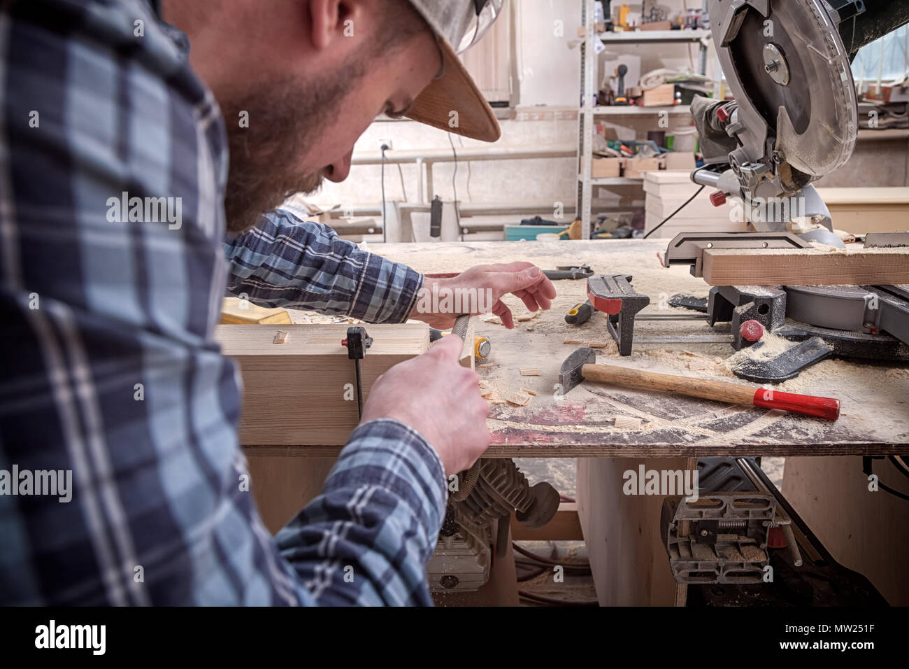 Close-up of craftsman hands in gloves measuring wooden plank with ruler ...
