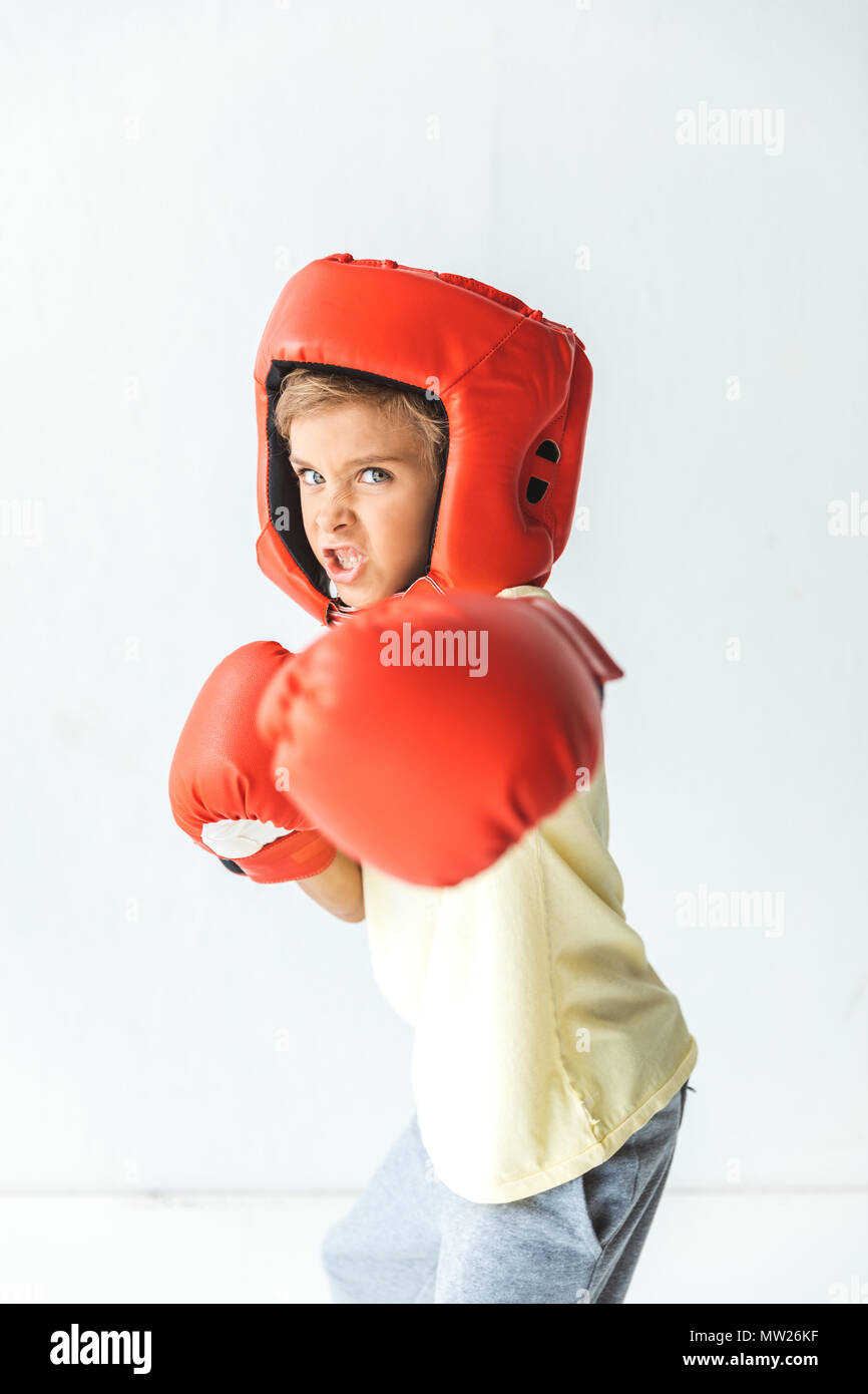 boy in boxing gloves and helmet fighting and looking at camera on white ...