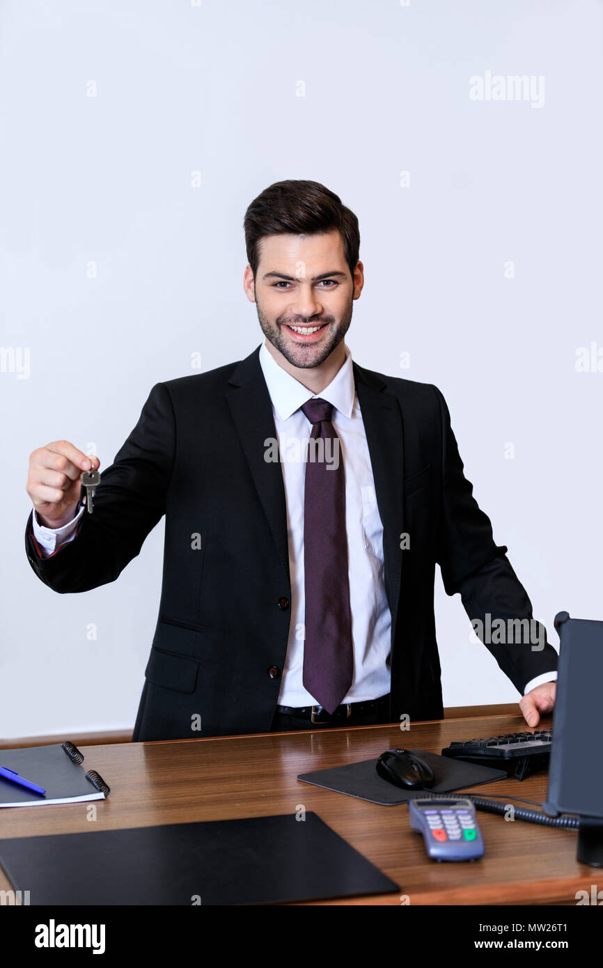 smiling handsome receptionist holding key at reception desk Stock Photo ...