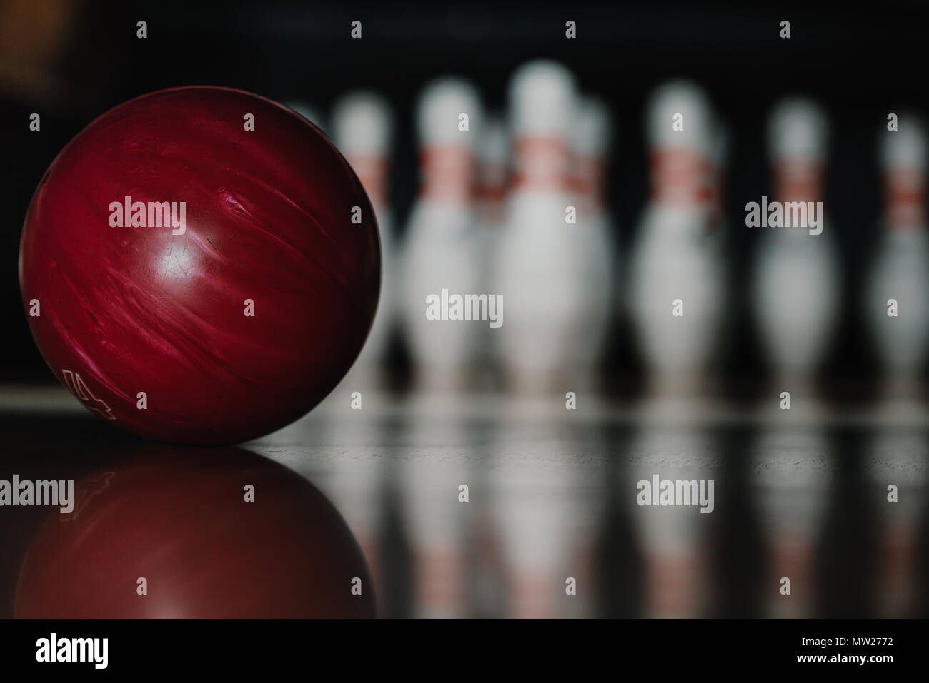 close-up shot of red bowling ball on alley in front of pins Stock Photo ...