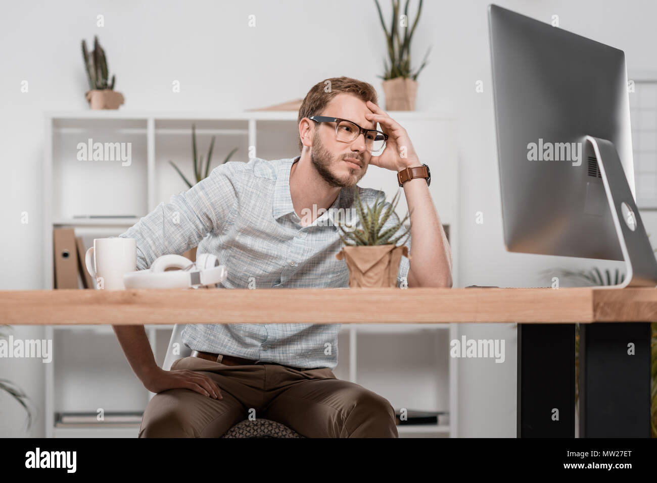 tired caucasian businessman looking at computer monitor while sitting ...