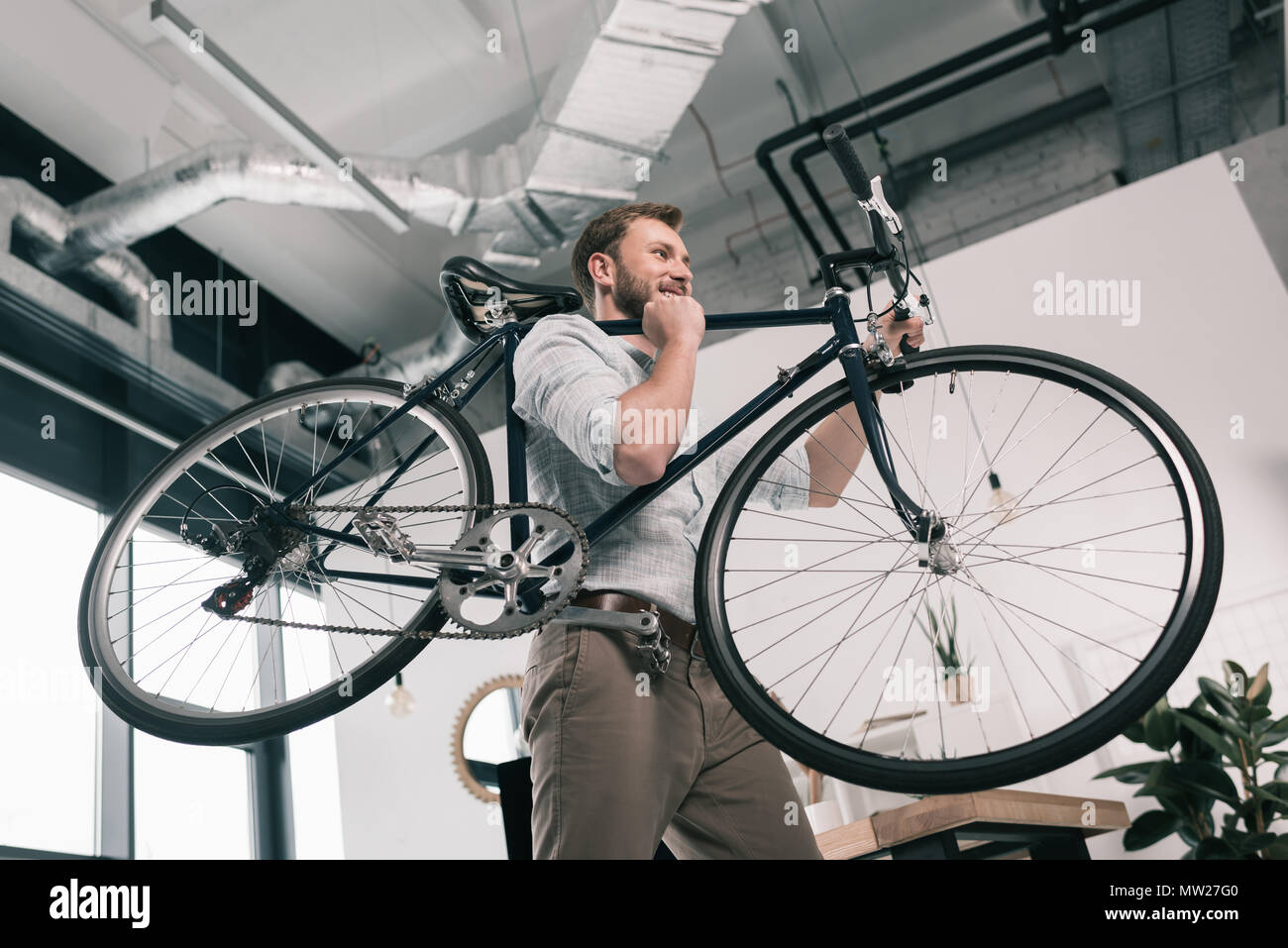bottom view of caucasian businessman standing and carrying bicycle in ...