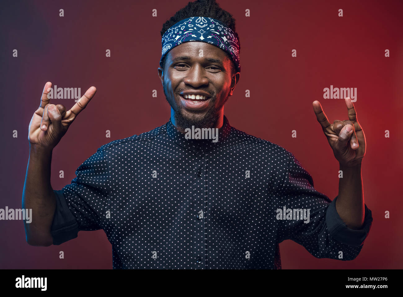 happy african american man showing rock signs isolated on burgundy ...