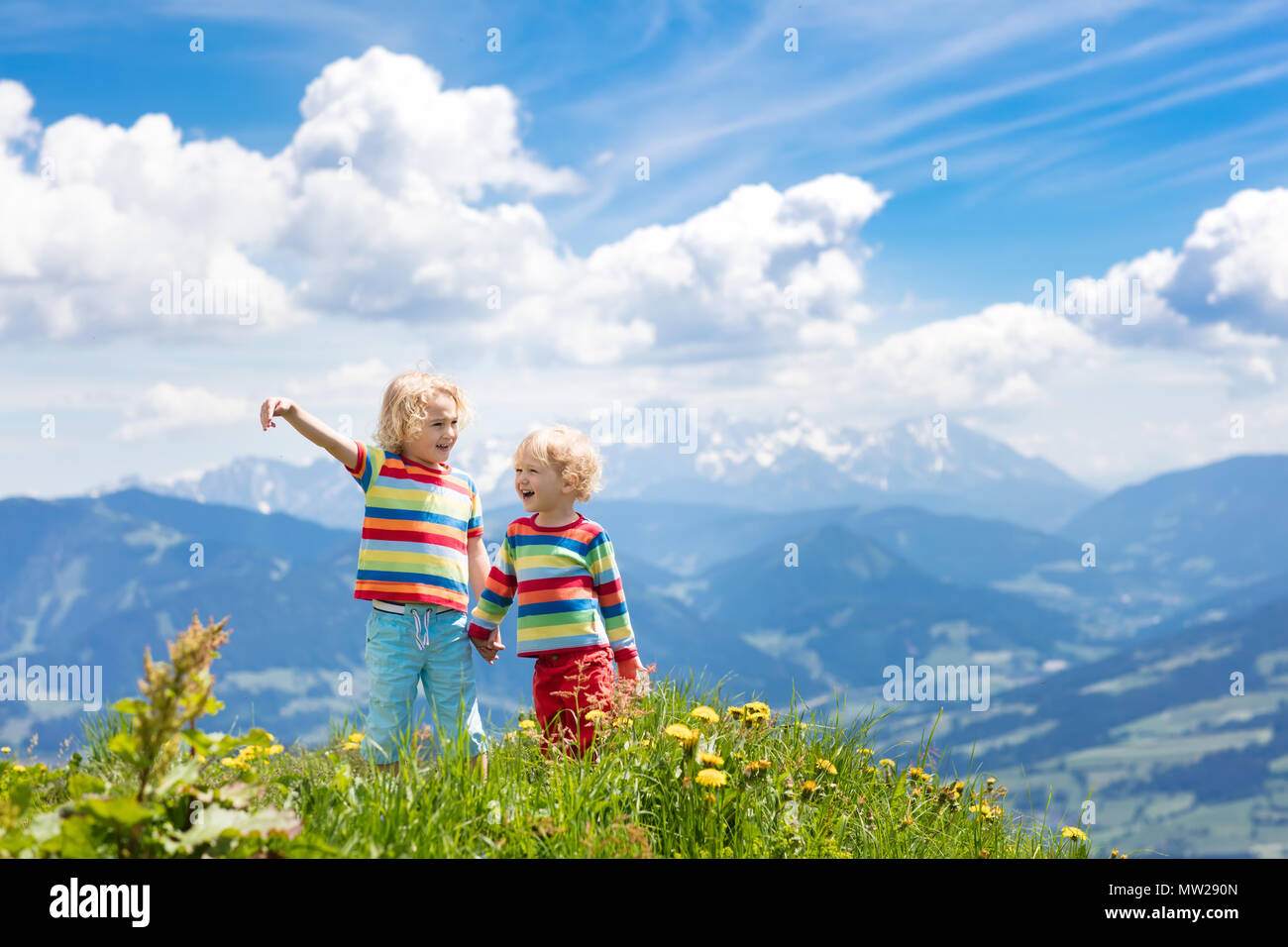 Children hiking in Alps mountains. Kids look at snow covered mountain ...