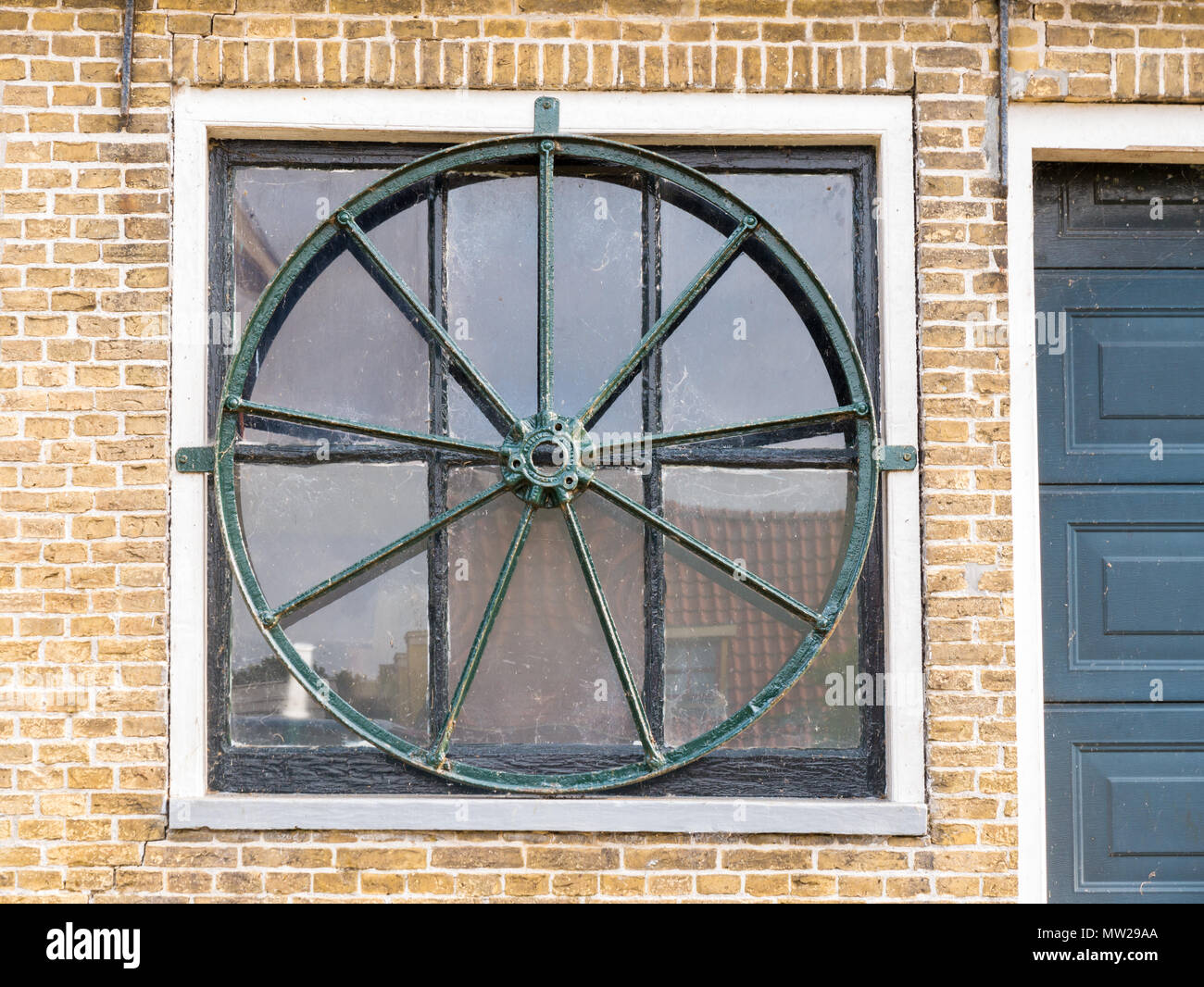 Glass window with round wheel of steel, detail of facade of old house ...