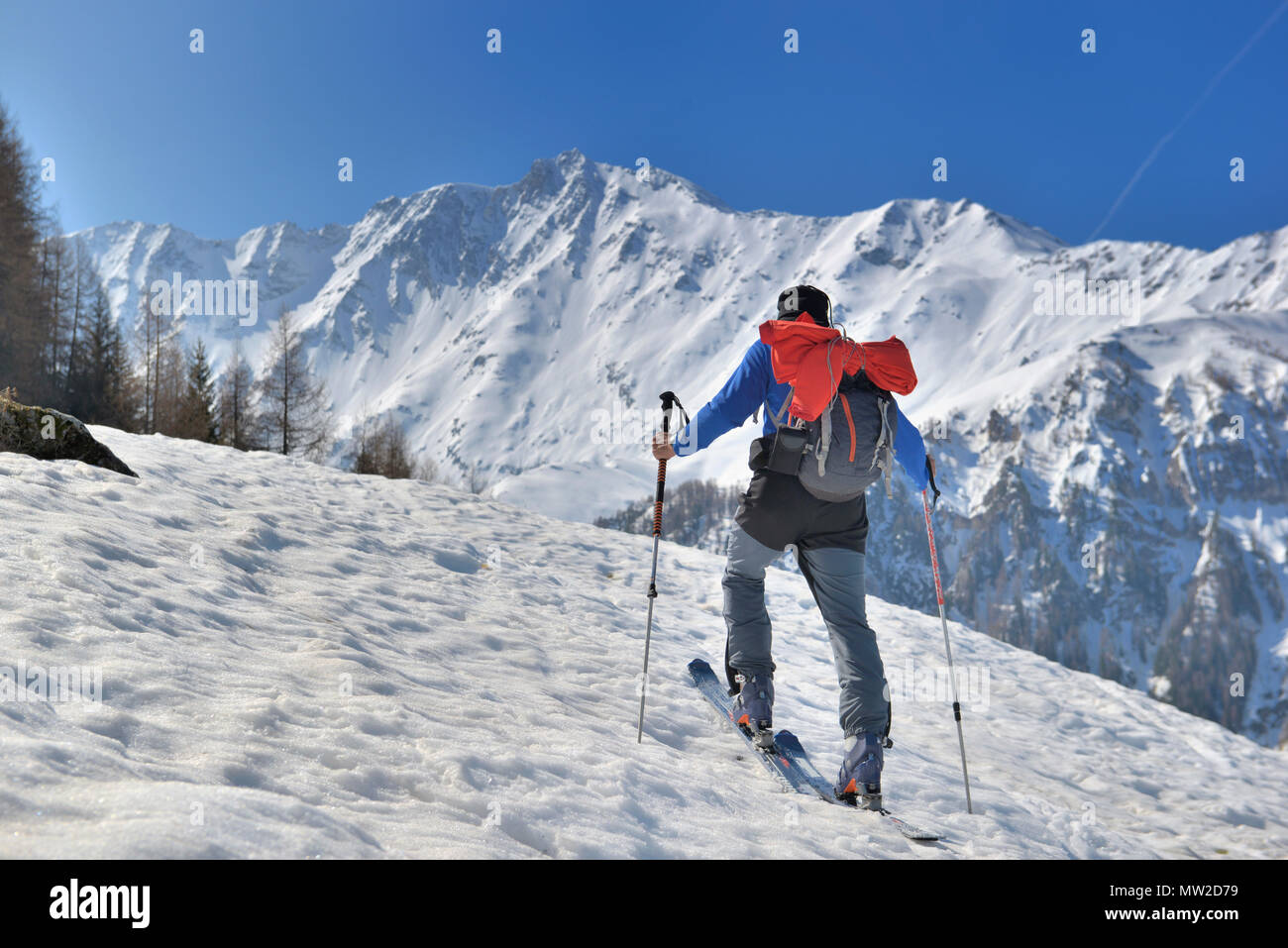 man climbing snowy mountain in touring ski under blue sky Stock Photo ...