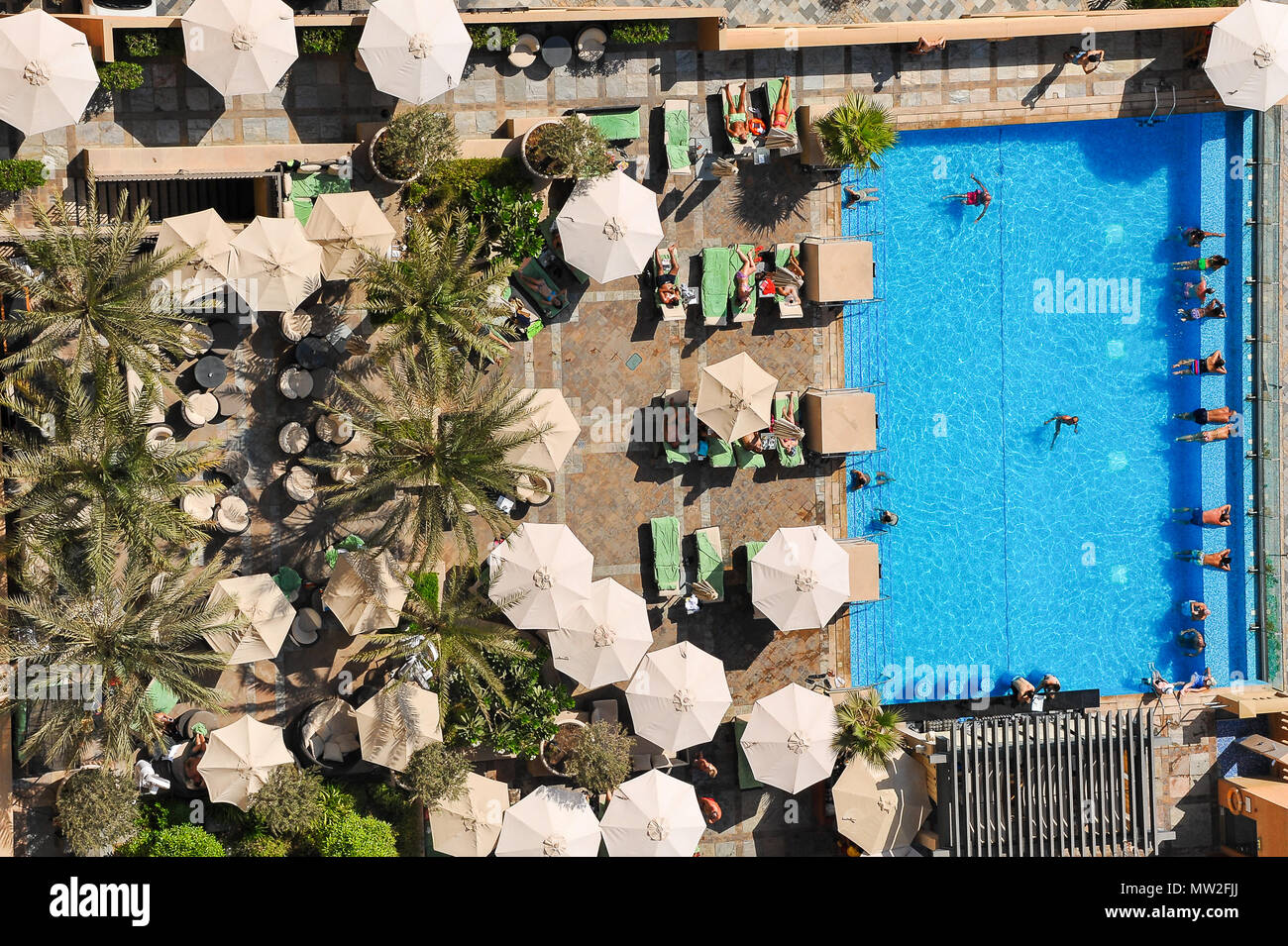 Aerial view to a resort swimming pool, with people relaxing under ...