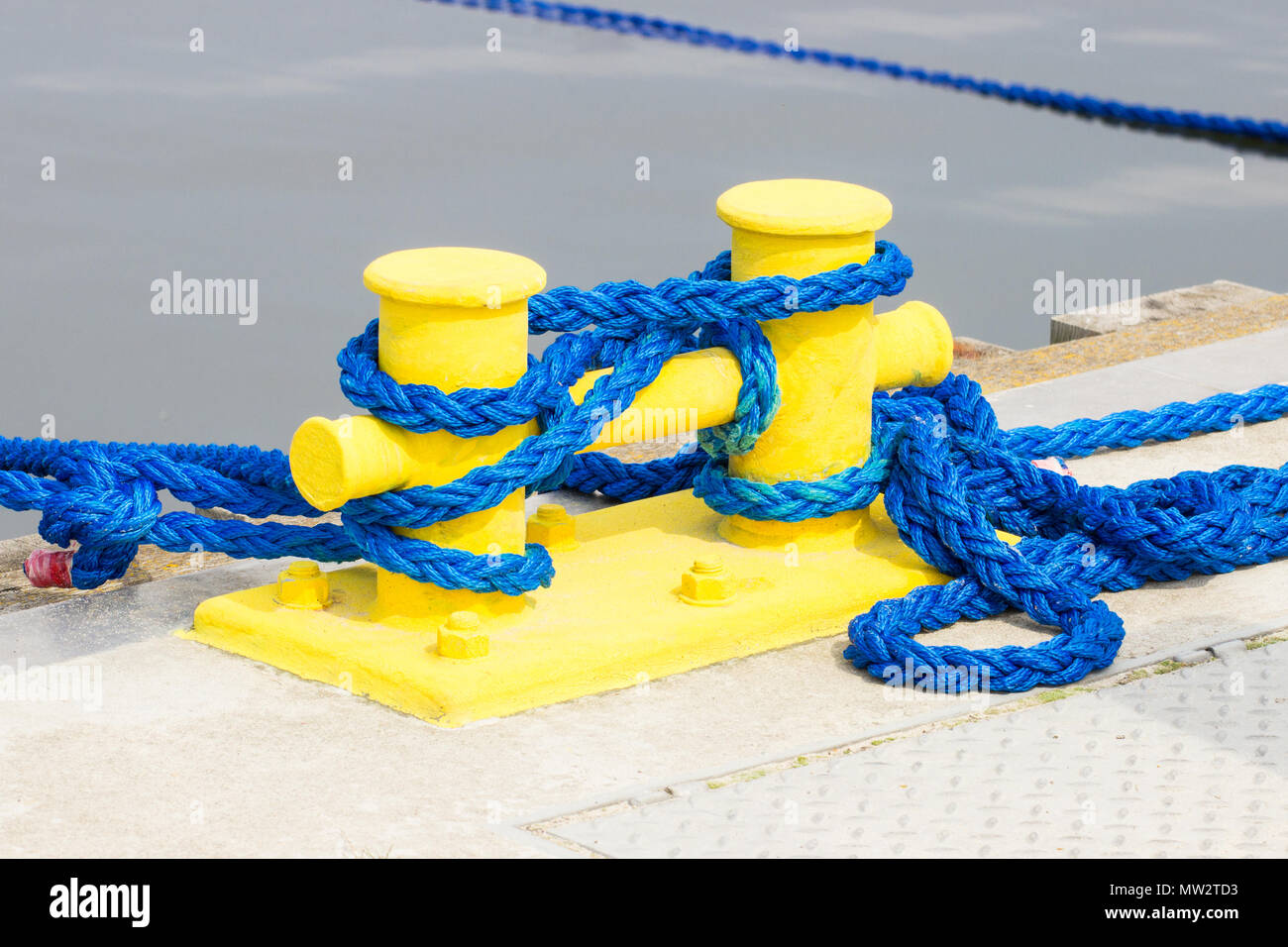 Blue rope and yellow mooring bollard in port, closeup and detail of ...