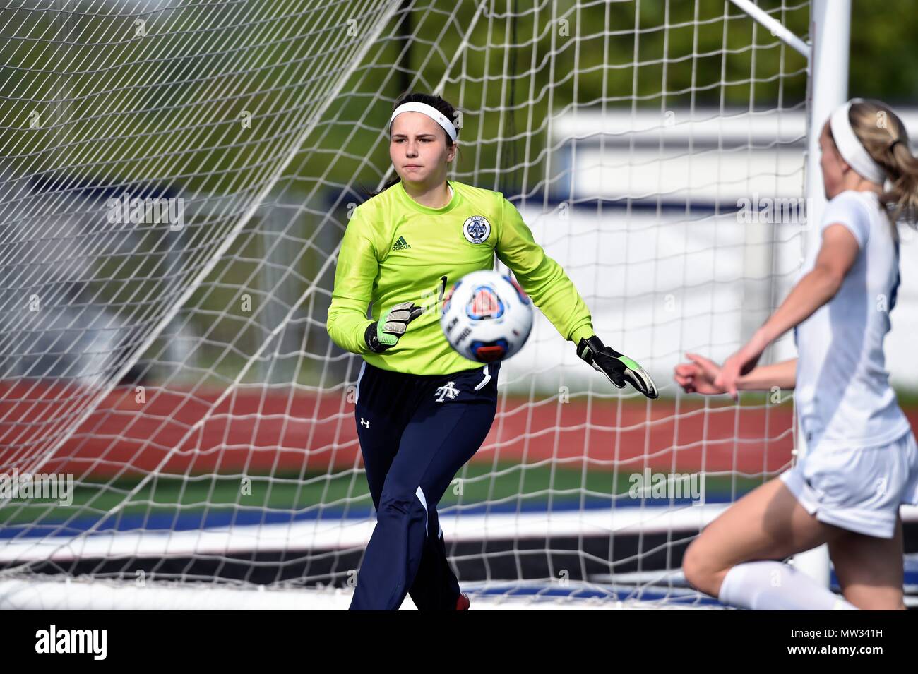 High school keeper attempting to get to an elevated ball in front of ...