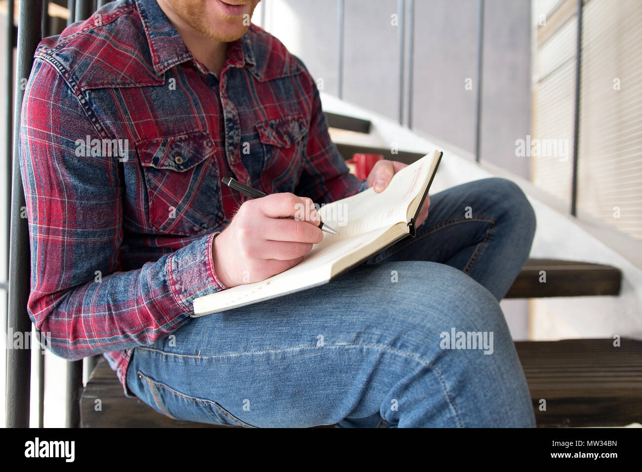 Man wearing casual clothes writing in his diary. Cropped picture of ...