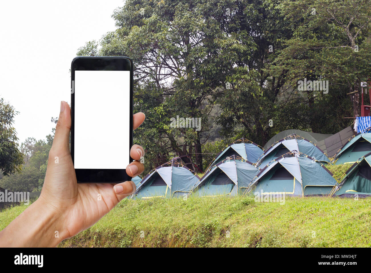 Hand holding black smartphone with white screen for mock up on camping ...