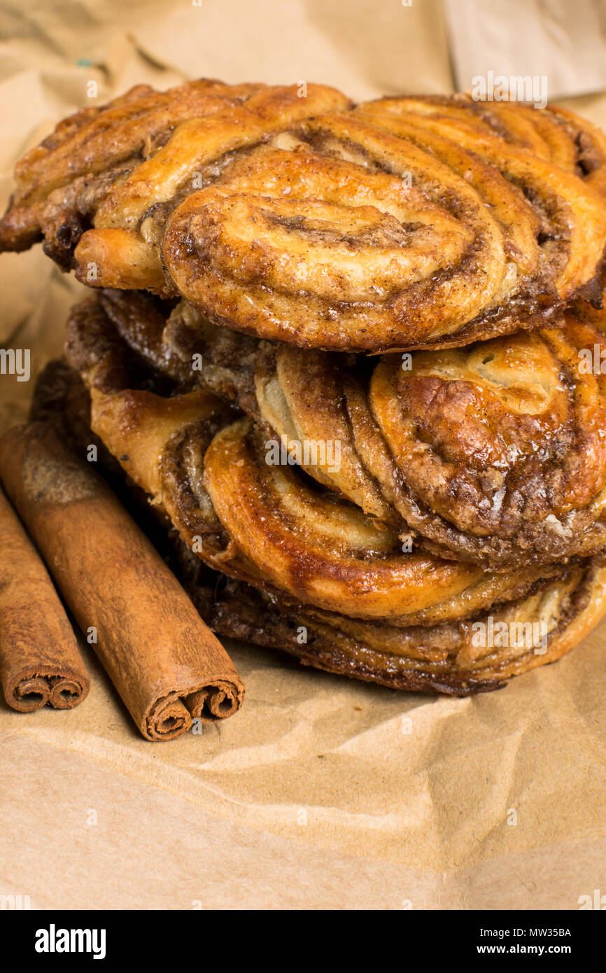 homemade sweet cinnamon rolls on paper bag with sticks of cinnamons ...