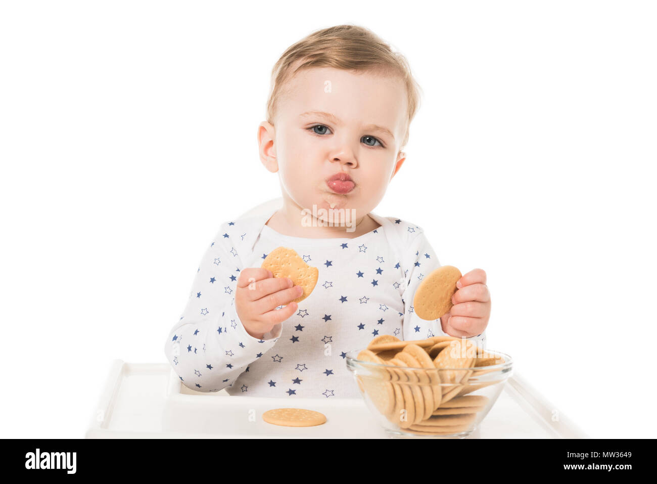 adorable baby boy eating cookies sitting in highchair isolated on white ...
