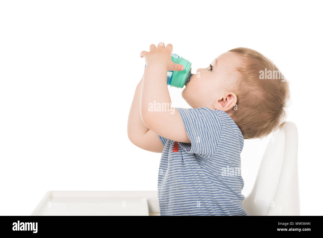 side view of little boy drinking water from baby cup and sitting in ...