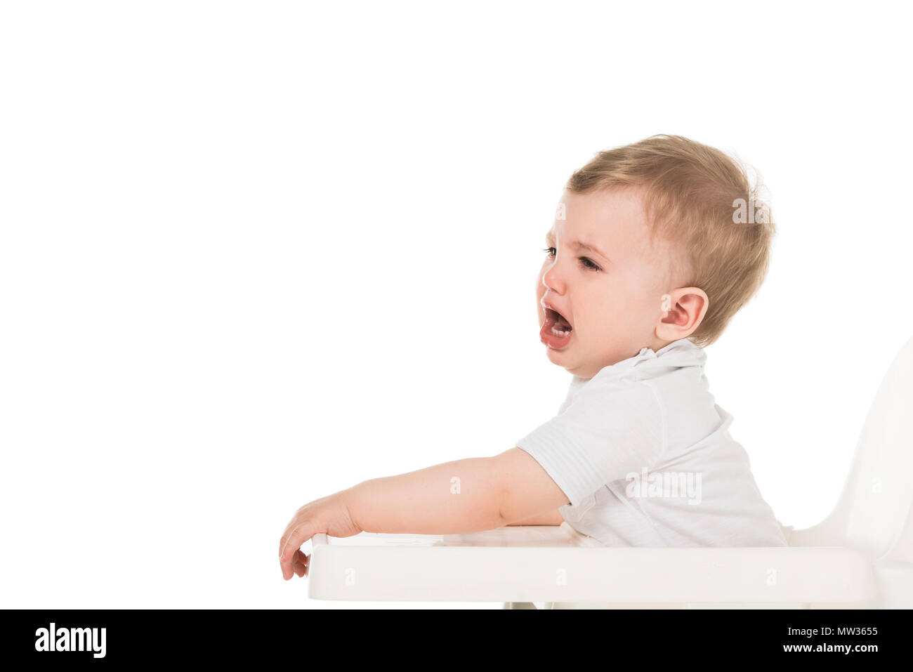 side view of crying baby boy in highchair isolated on white background ...