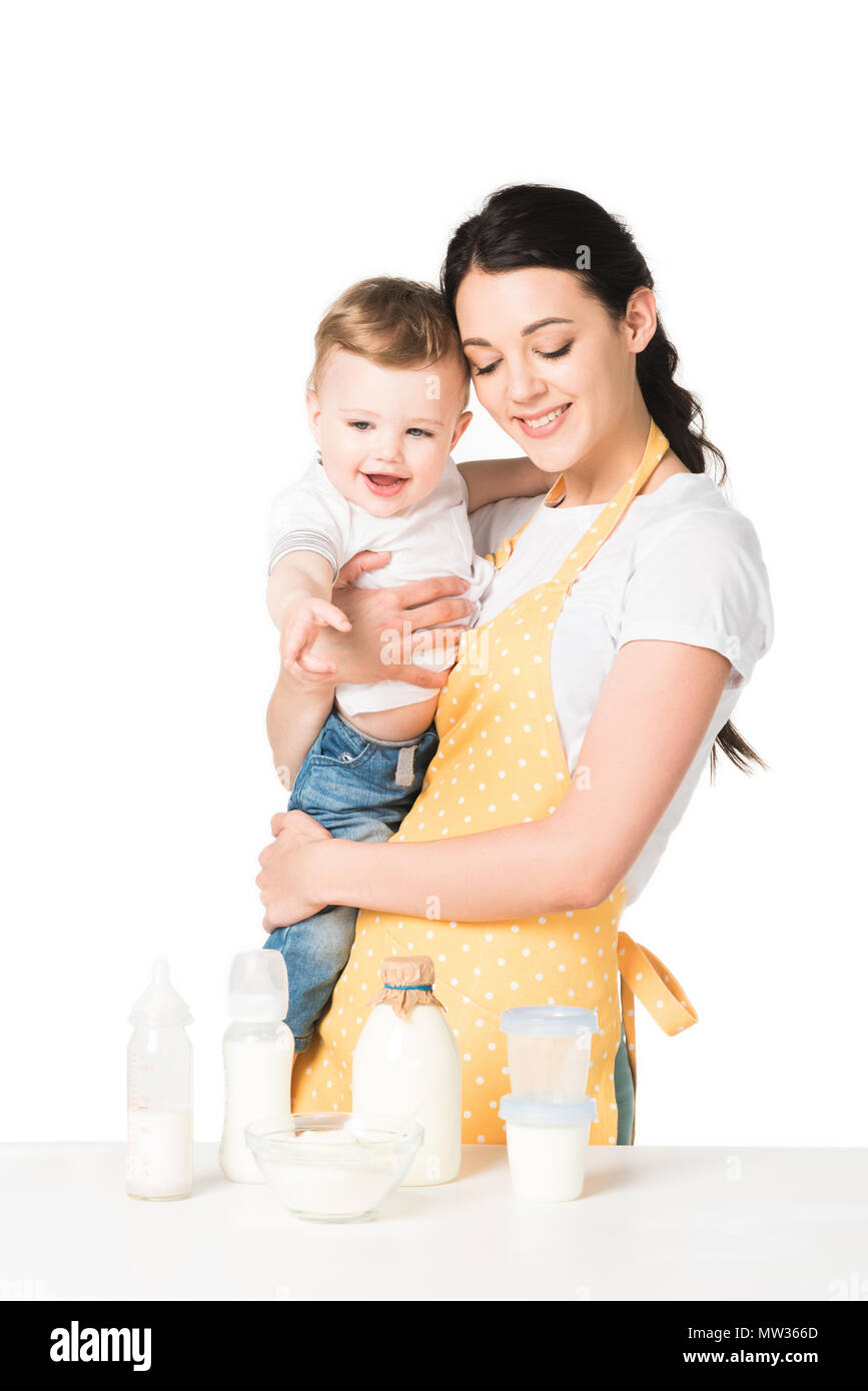 happy mother in apron holding baby boy at table with children food ...