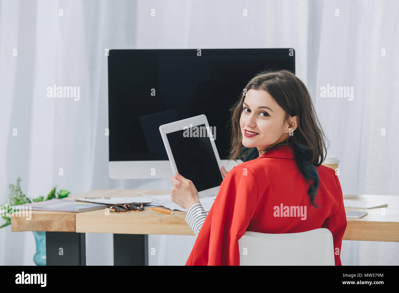 Pretty lady holding tablet by working table with computer Stock Photo ...