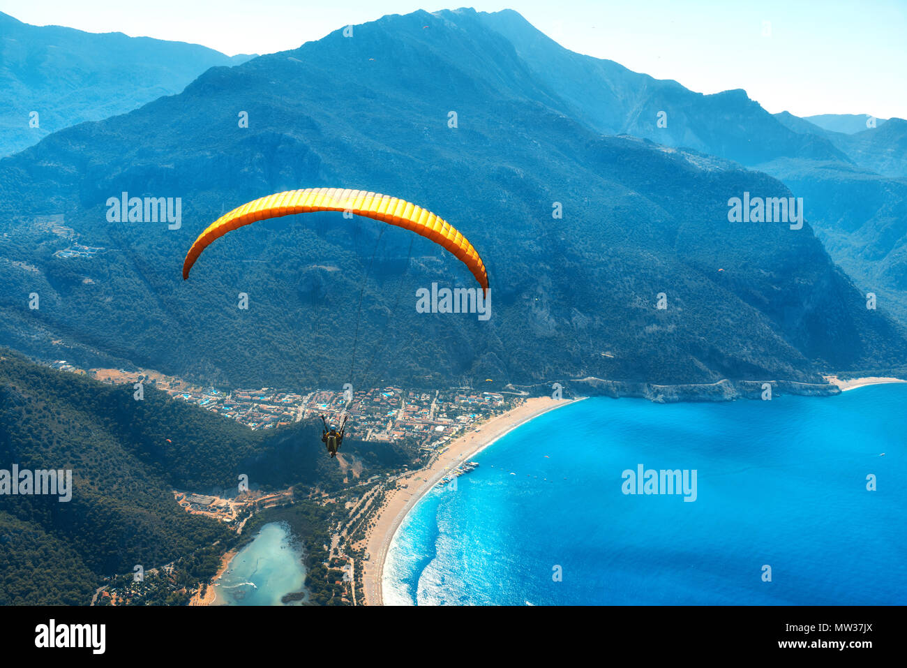 Paragliding in the sky. Paraglider tandem flying over the sea with blue ...