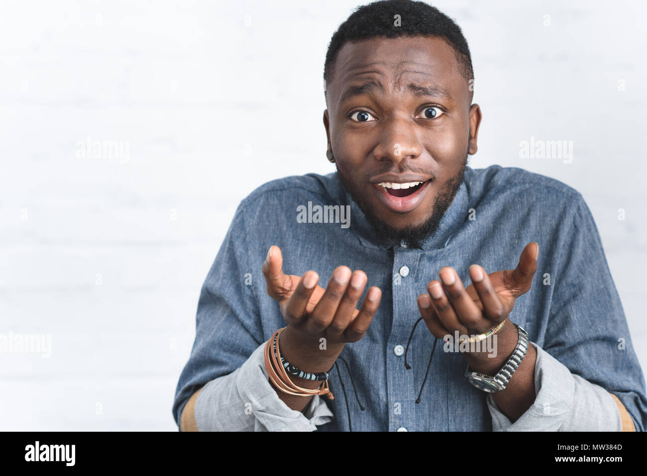 Surprised young african american man by white wall Stock Photo - Alamy