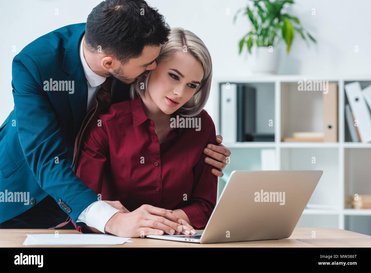businessman flirting with beautiful female colleague using laptop in ...