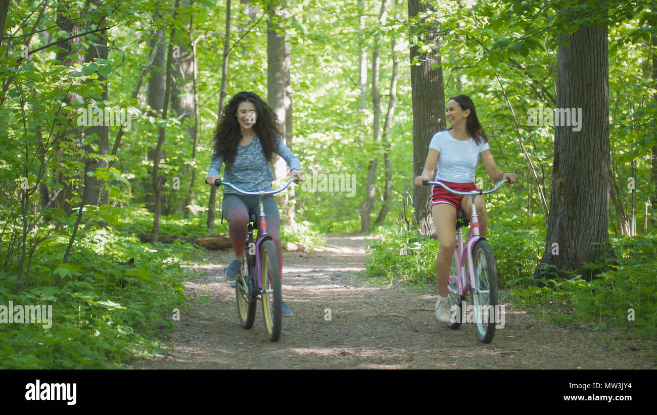Two girls climb the path to the hill in the green forest, one girl ...