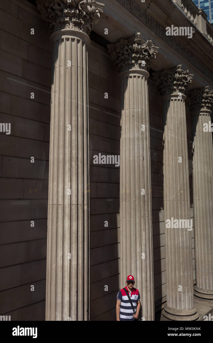 A man waits for a bus beneath the pillars and columns of the Bank of ...