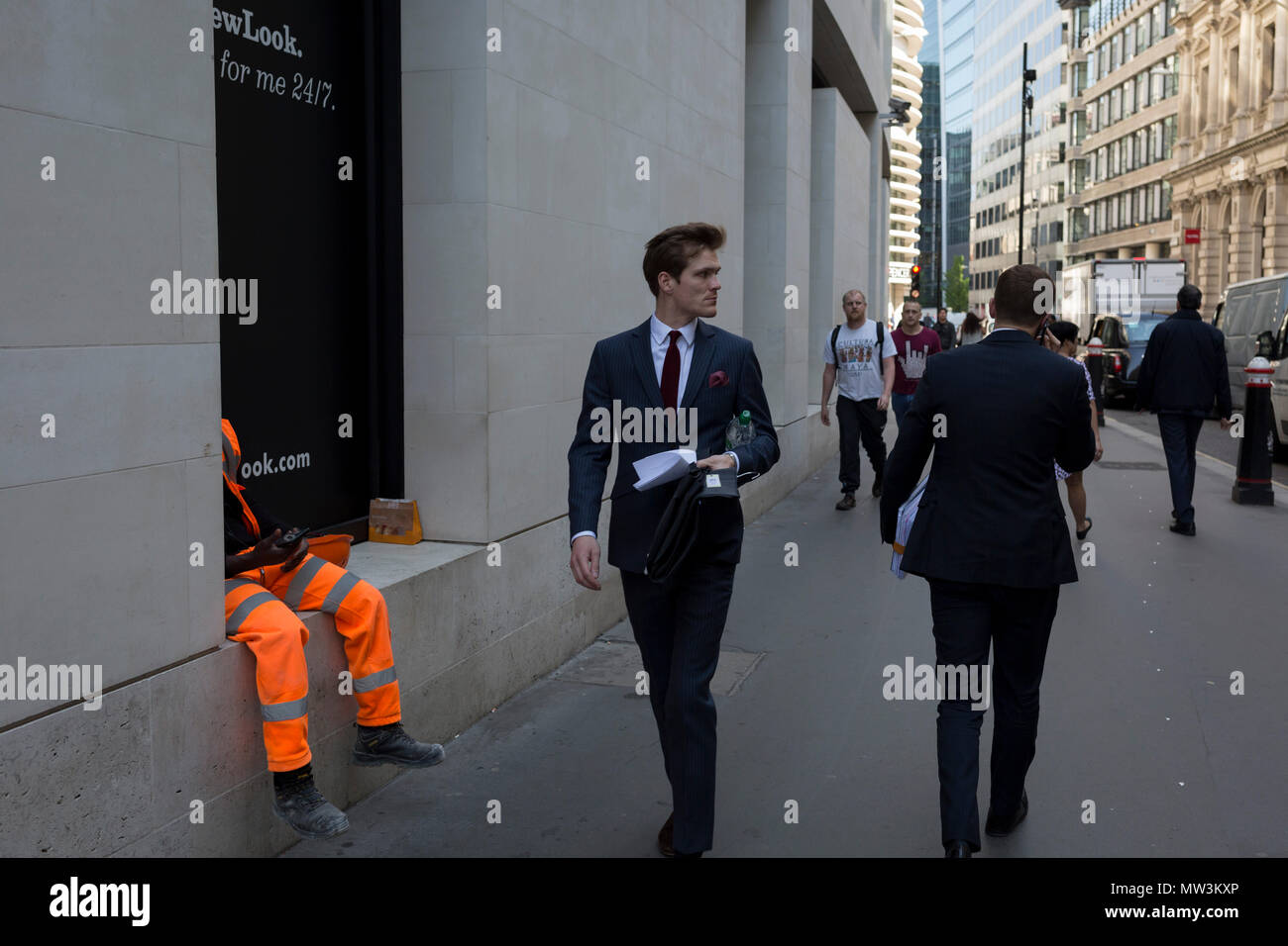 The legs of a workman wearing hi-vis and a City businessman in a suit ...
