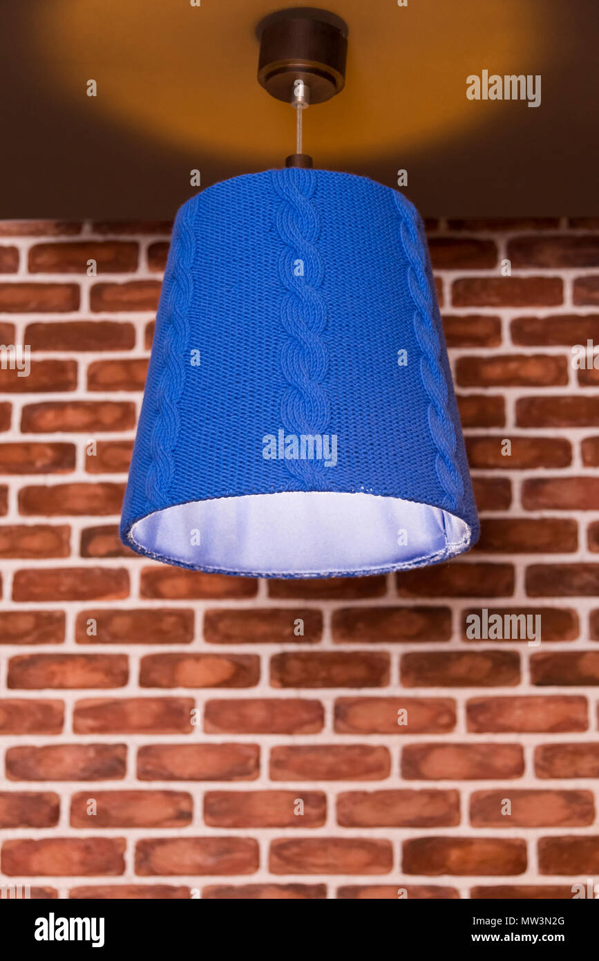 An original knitted lamp hanging on a wall against a brick wall ...