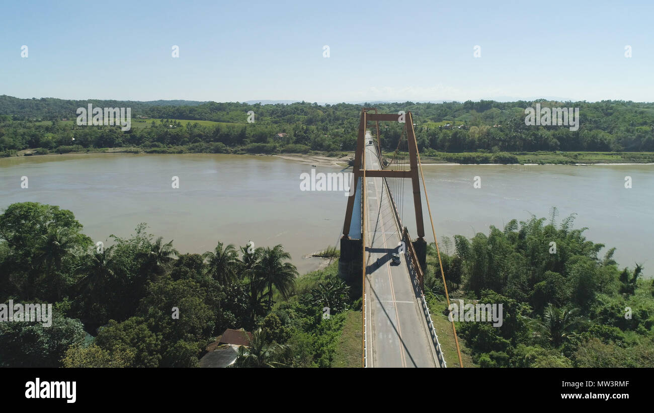 Aerial view of modern bridge with cars over tropical river in mountain ...