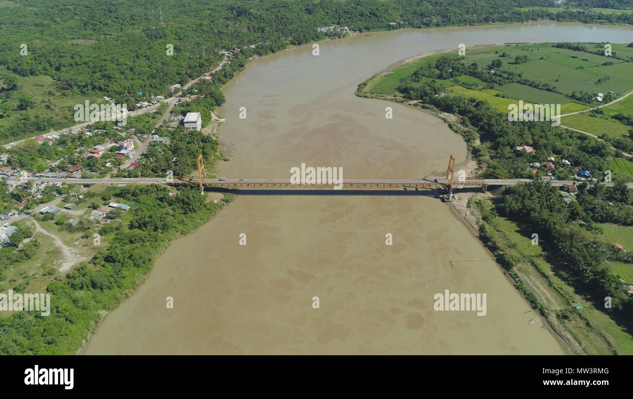 Aerial view of modern bridge with cars over tropical river in mountain ...